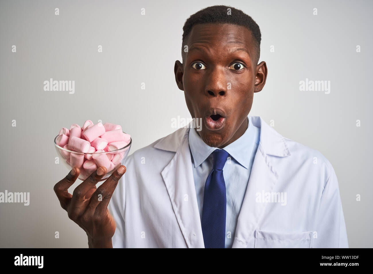 African american doctor man holding bowl with marshmallow over isolated ...