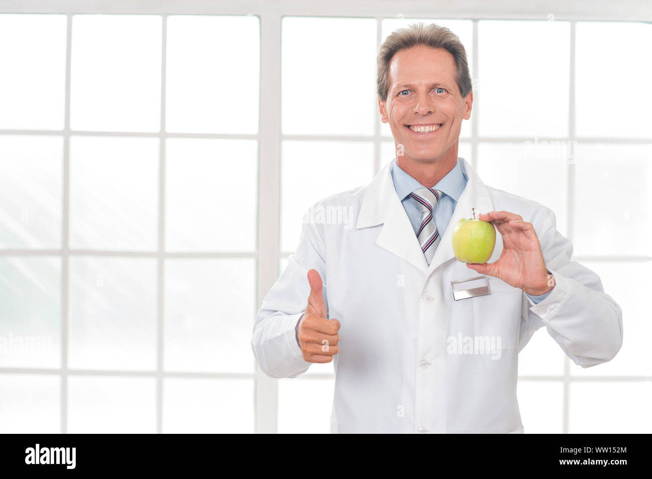Senior doctor at his office in hospital working thumb up healthy food ...