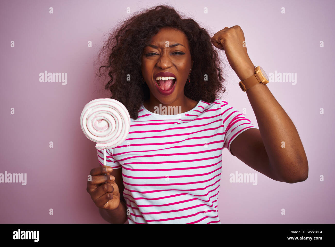 Young african american woman eating sweet candy standing over isolated ...