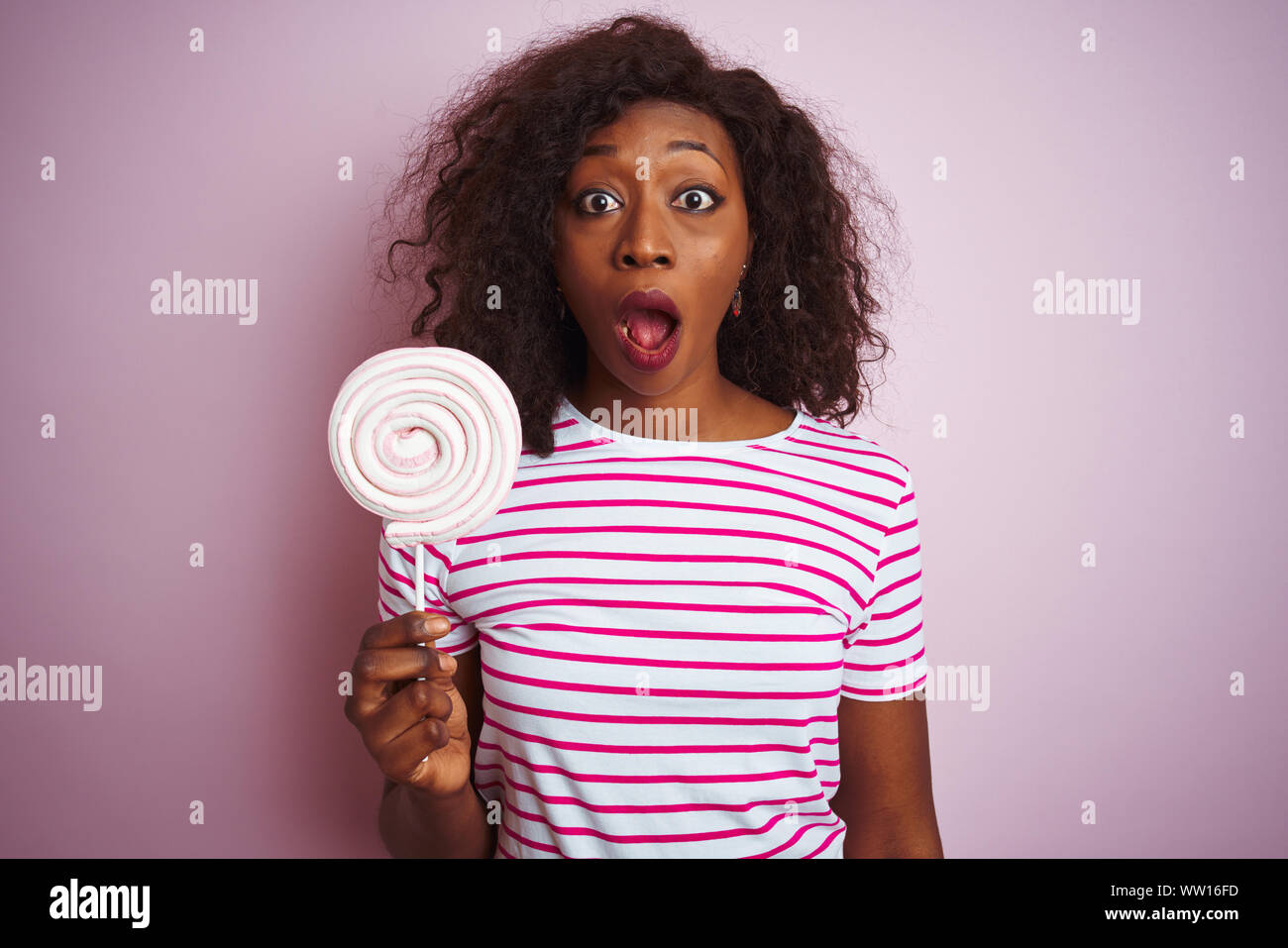 Young african american woman eating sweet candy standing over isolated ...