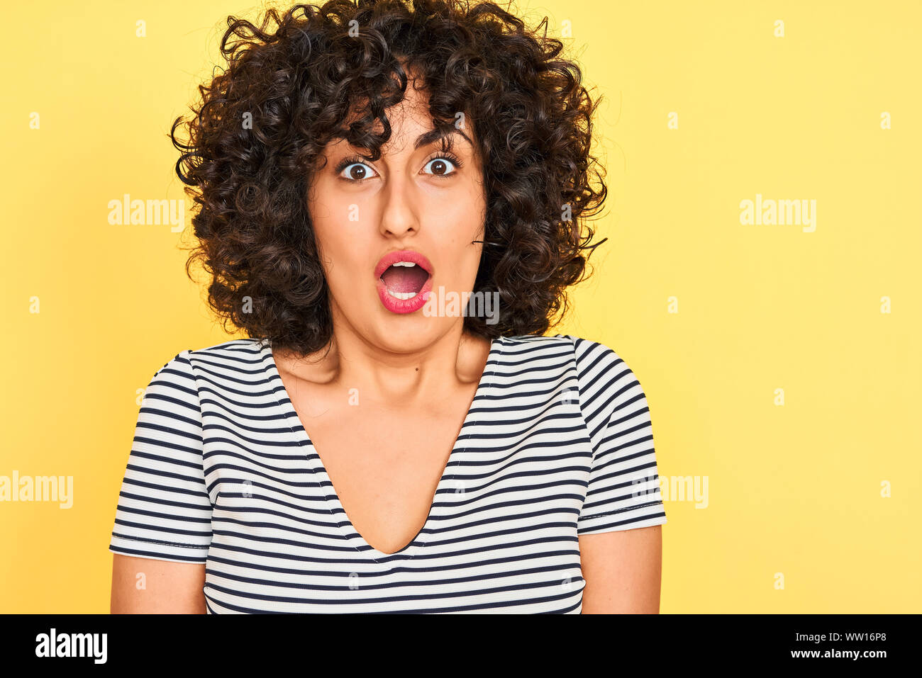 Young arab woman with curly hair wearing striped dress over isolated ...