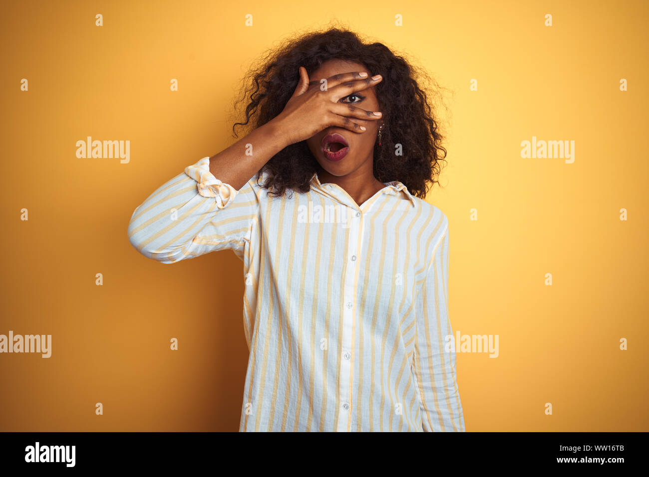 African american woman wearing striped shirt standing over isolated ...