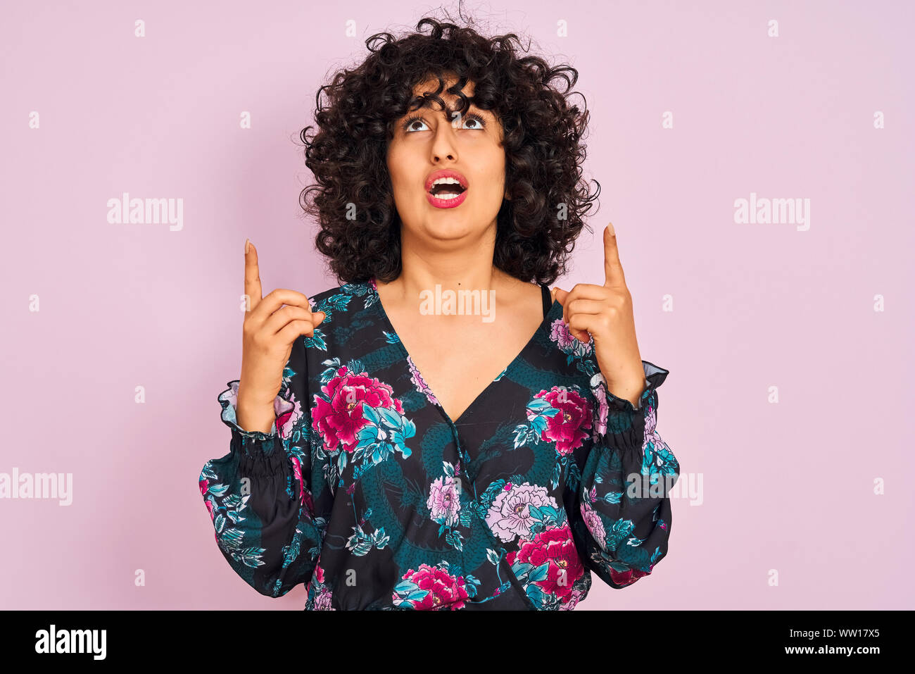 Young arab woman with curly hair wearing floral dress over isolated ...