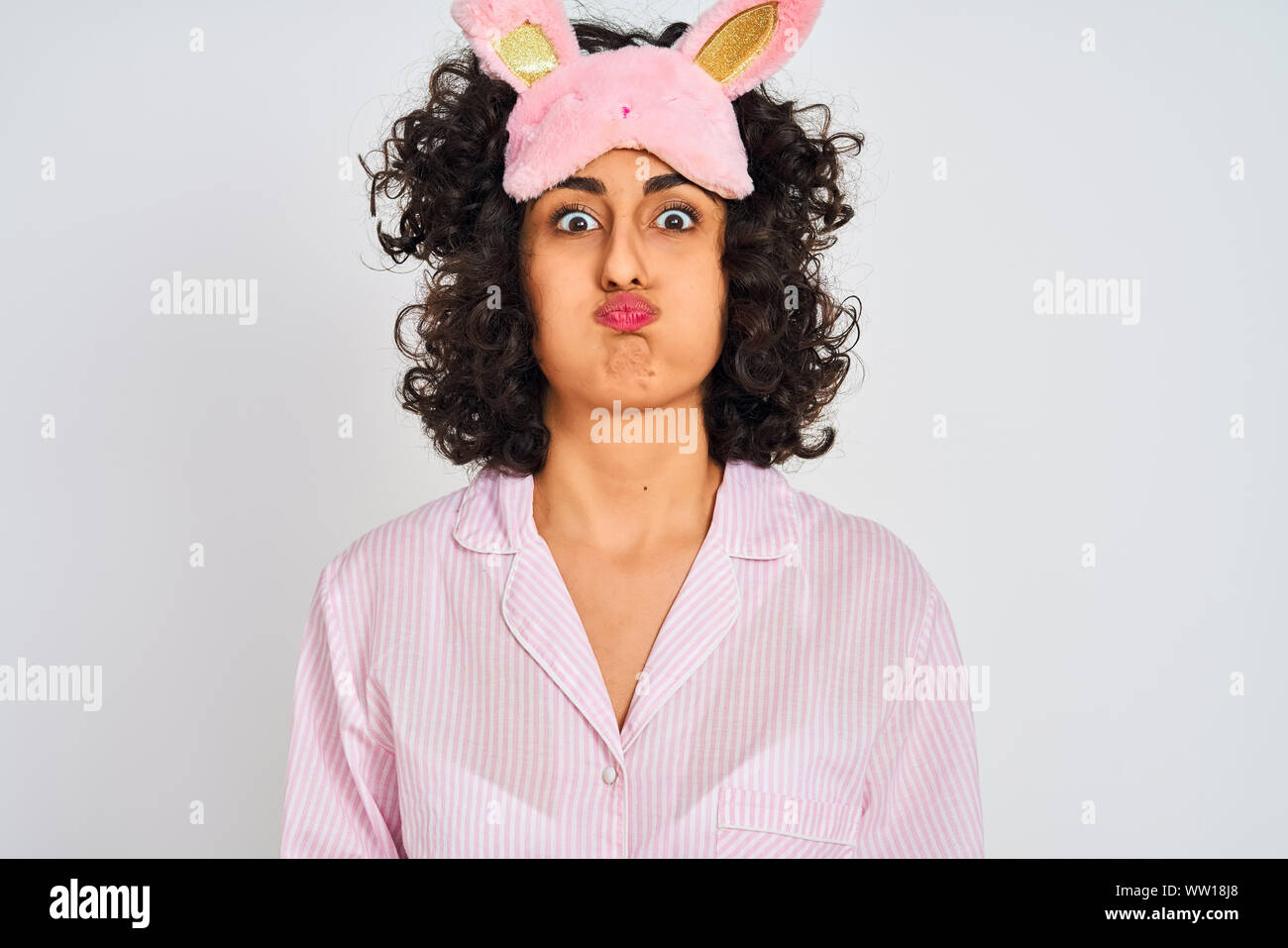 Arab woman with curly hair wearing pajama and sleep mask over isolated ...