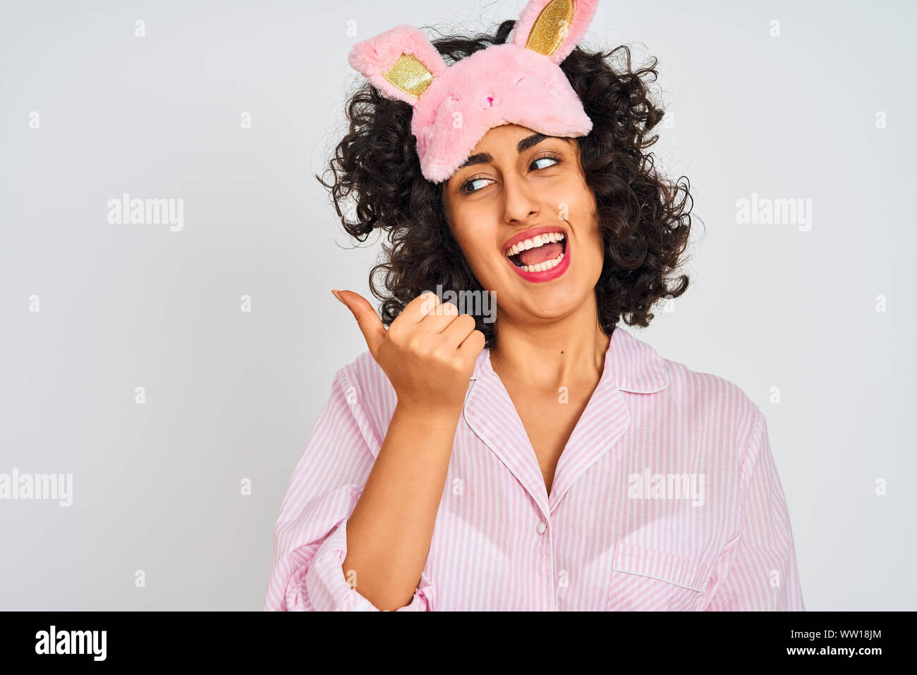 Arab woman with curly hair wearing pajama and sleep mask over isolated ...