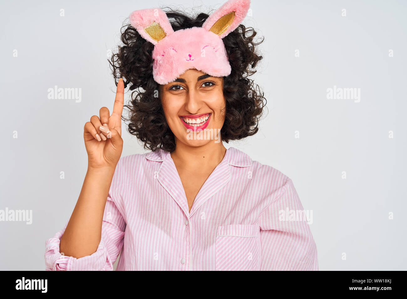 Arab woman with curly hair wearing pajama and sleep mask over isolated ...