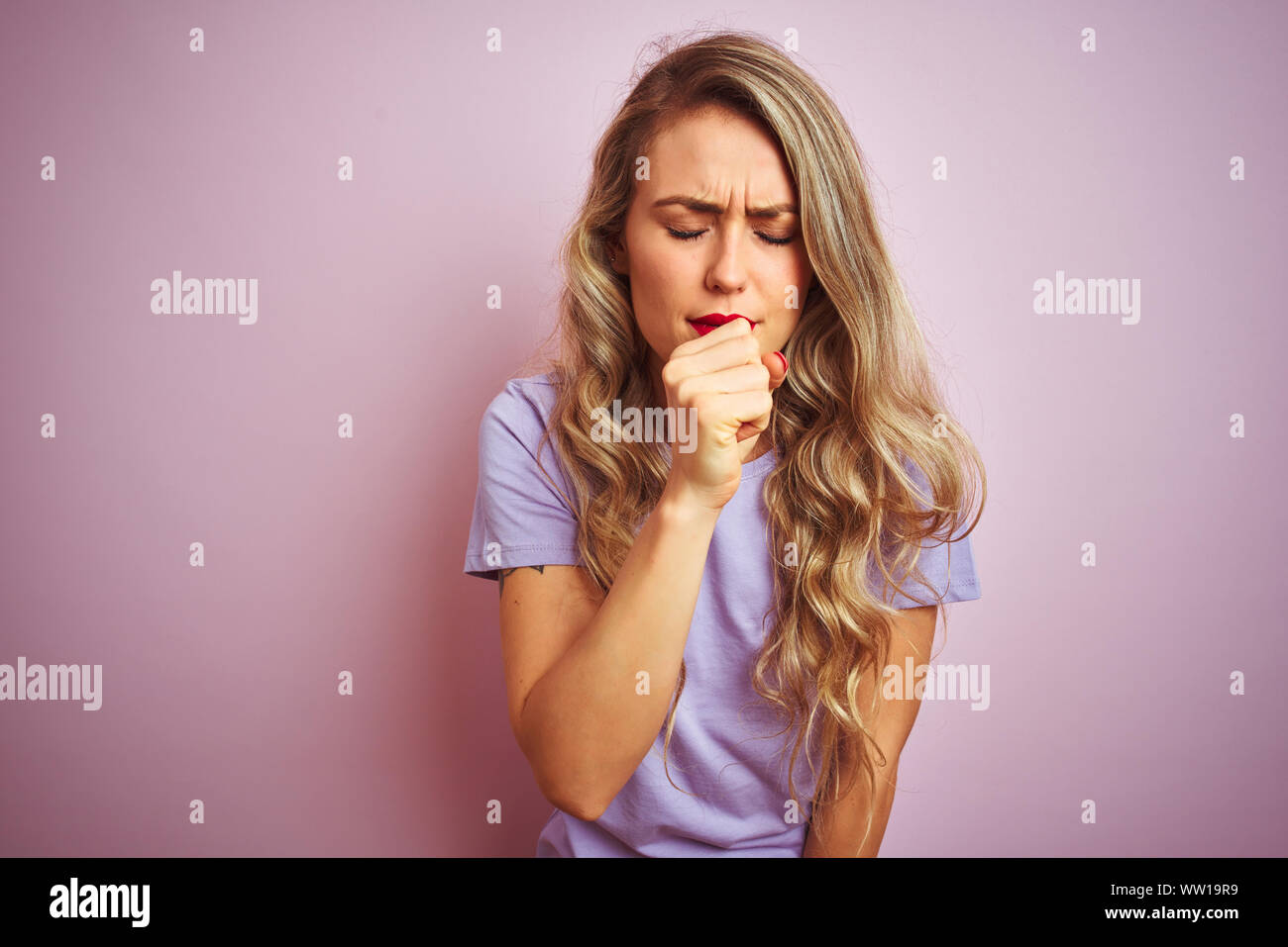 Young beautiful woman wearing purple t-shirt standing over pink ...