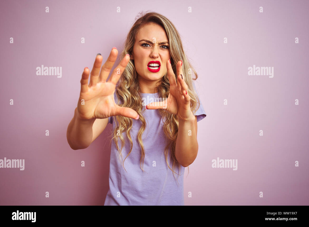 Young beautiful woman wearing purple t-shirt standing over pink ...