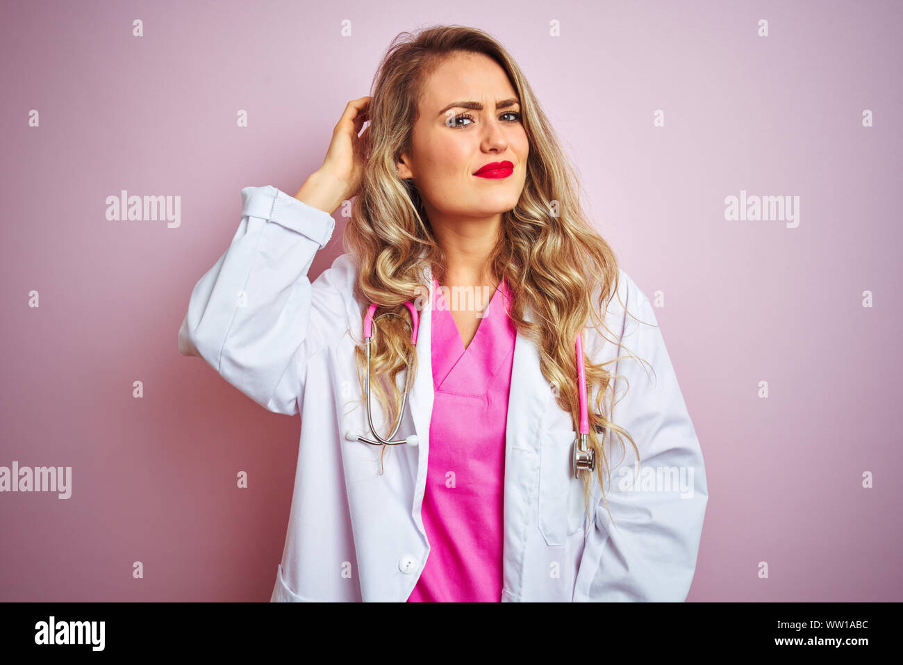 Young beautiful doctor woman using stethoscope over pink isolated ...