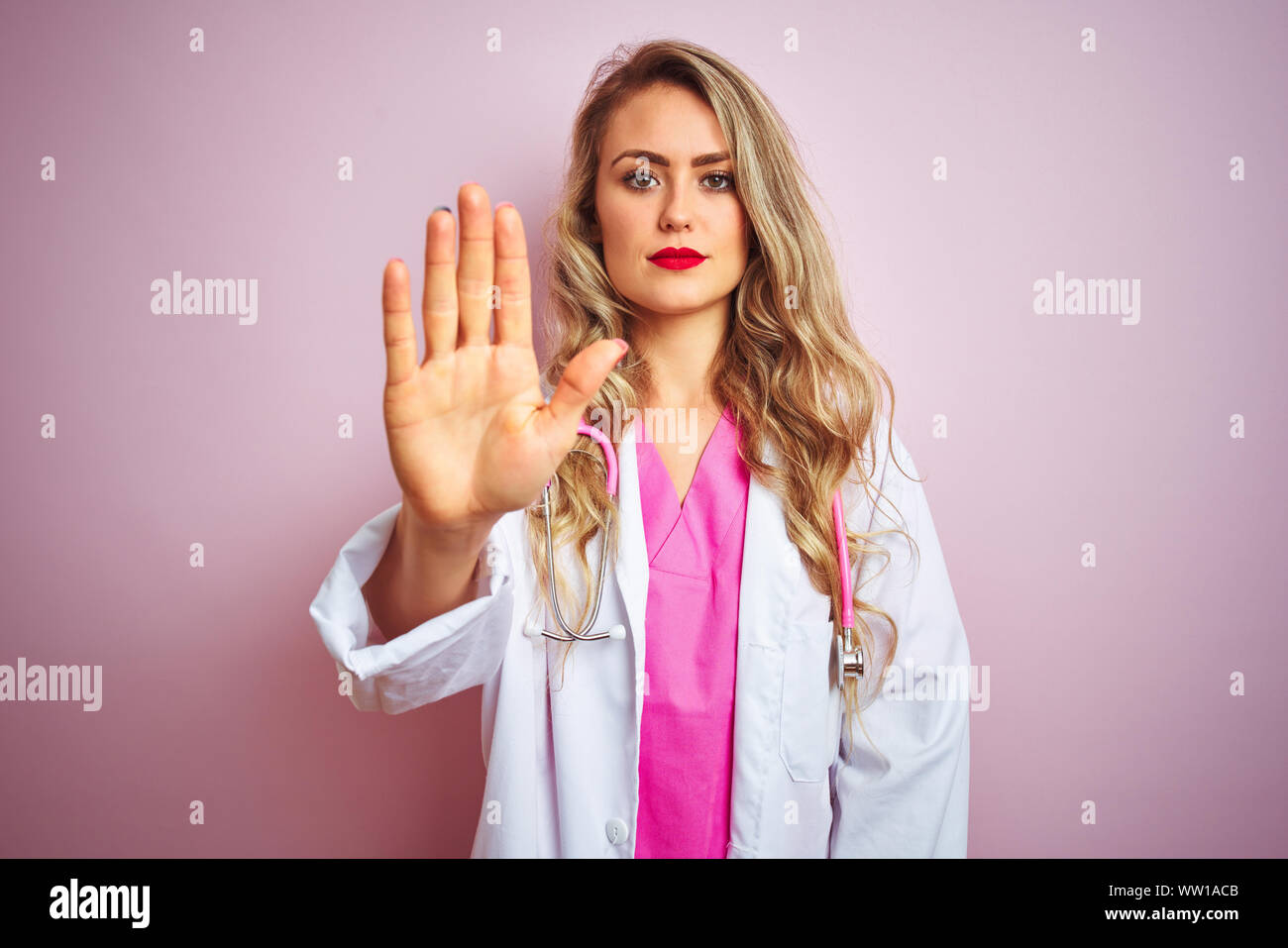 Young beautiful doctor woman using stethoscope over pink isolated ...