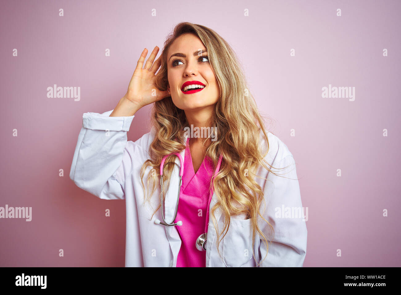 Young beautiful doctor woman using stethoscope over pink isolated ...