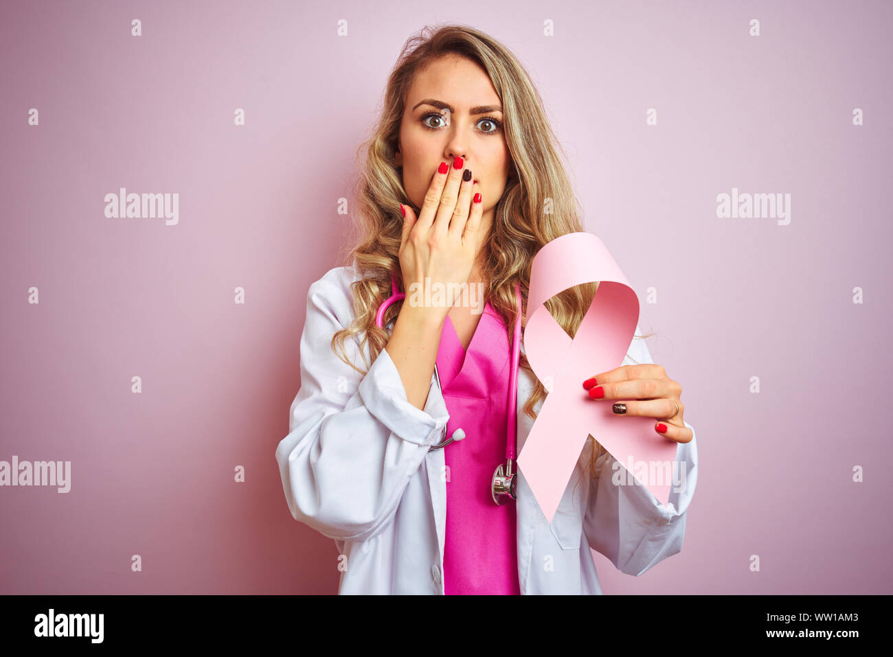 Young beautiful doctor woman holding cancer ribbon over pink isolated ...