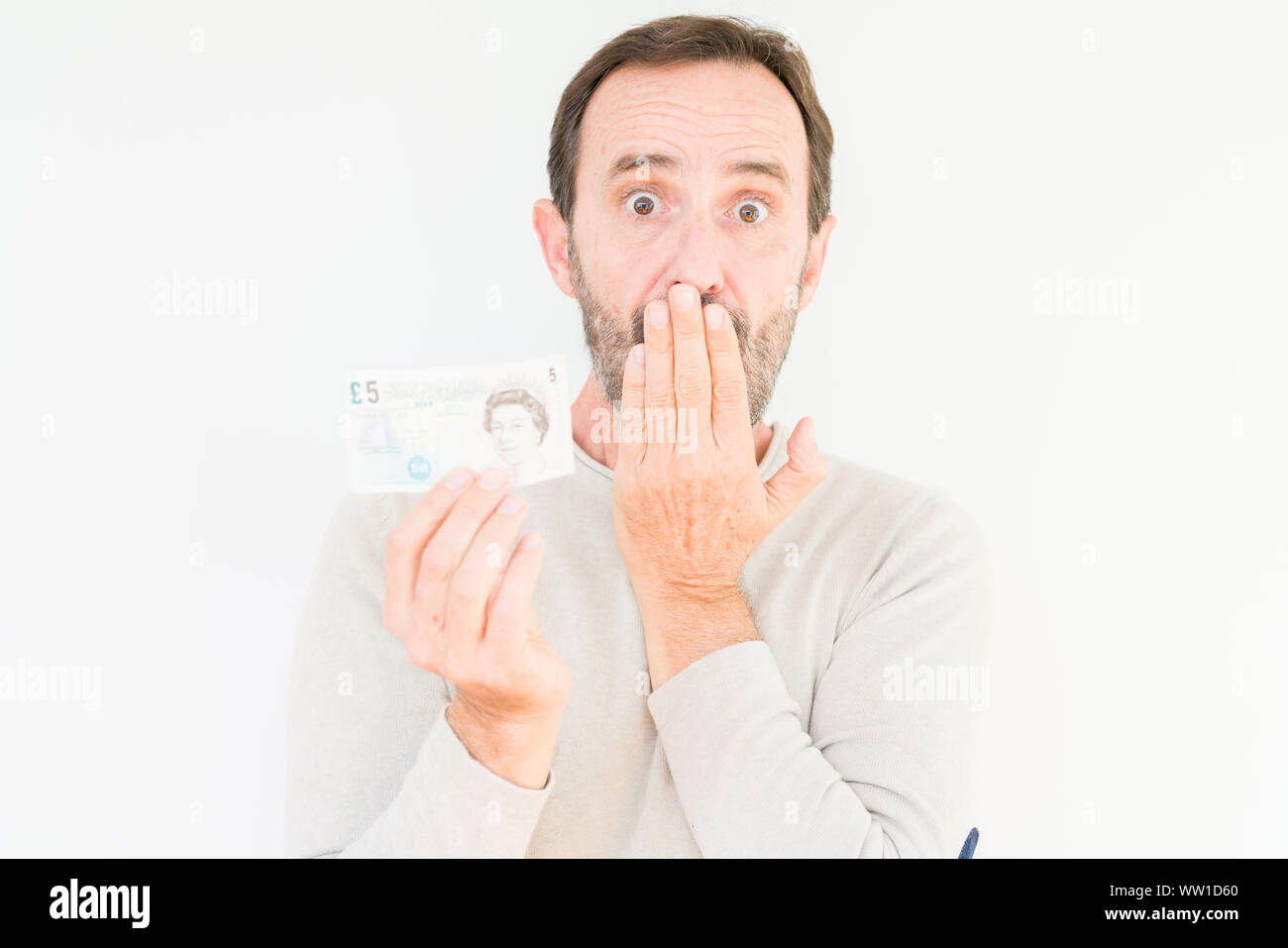 Senior man holding five pounds bank note over isolated background cover ...