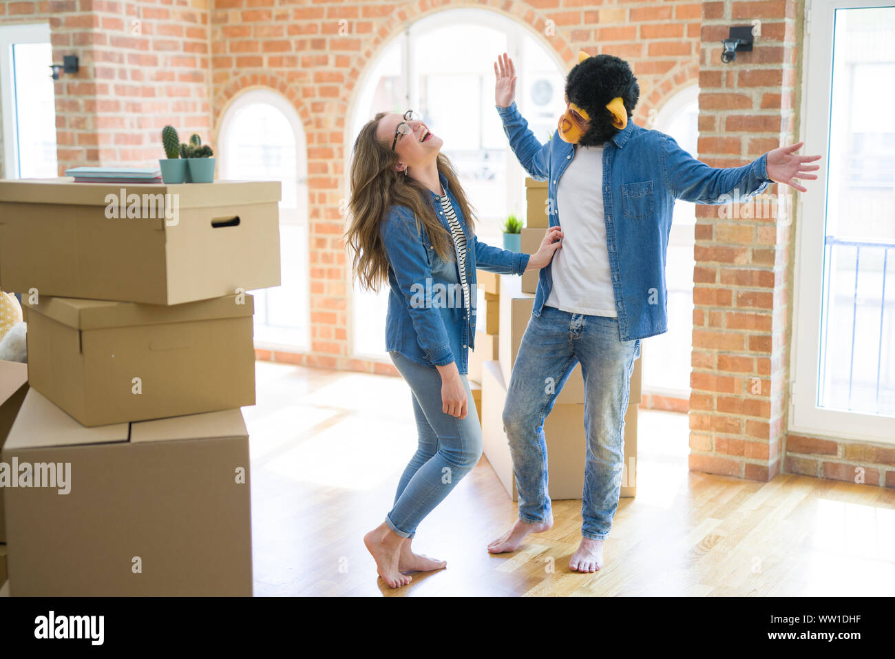 Young couple having fun wearing a monkey mask moving to a new apartment ...
