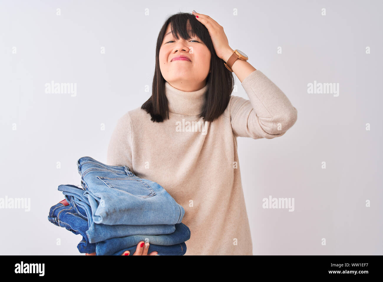 Beautiful Chinese shopkeeper woman holding folded jeans over isolated ...
