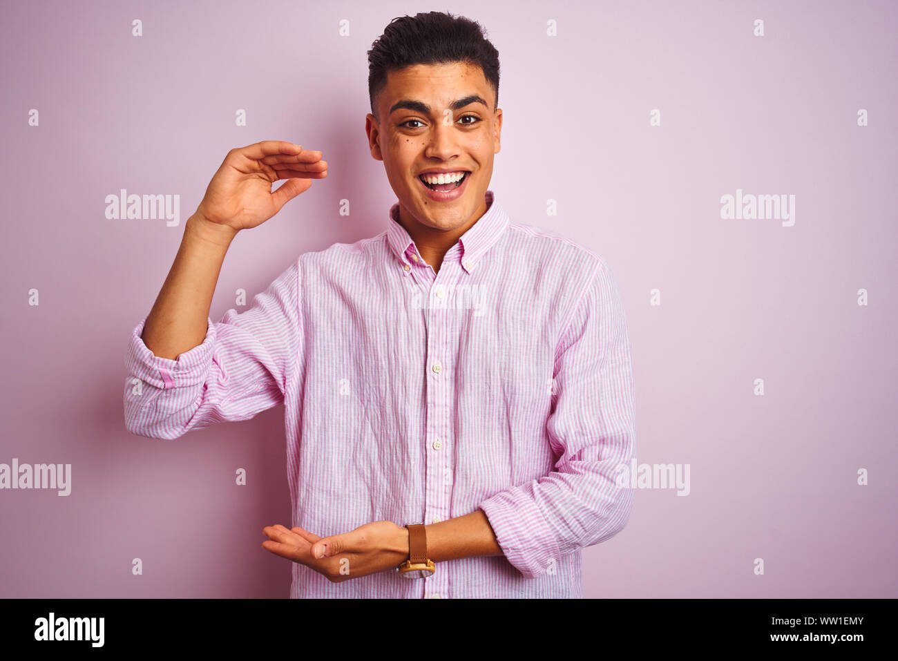 Young brazilian man wearing shirt standing over isolated pink ...