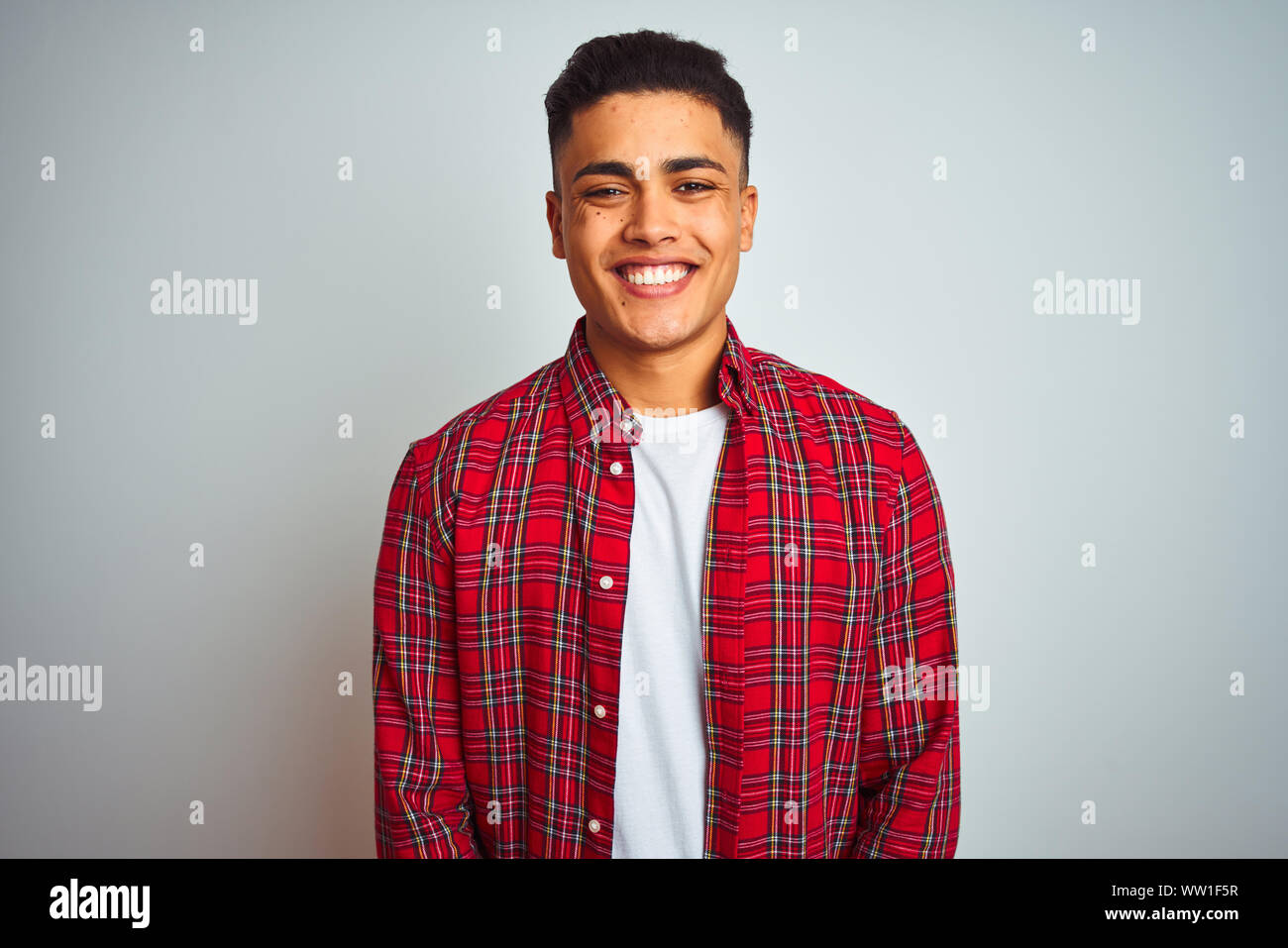 Young brazilian man wearing red shirt standing over isolated white ...