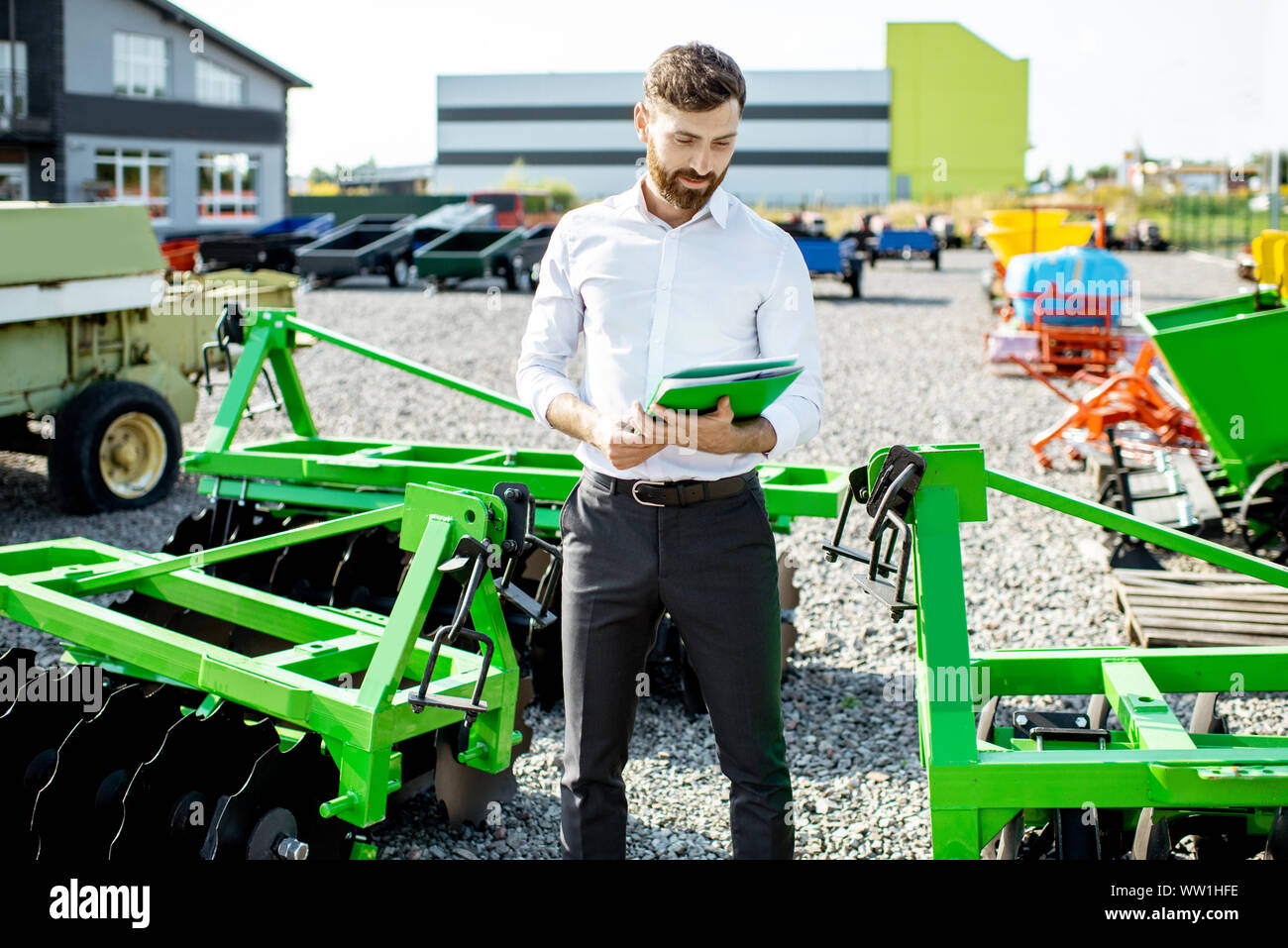 Portrait of a handsome salesman standing near the plow at the outdoor ...