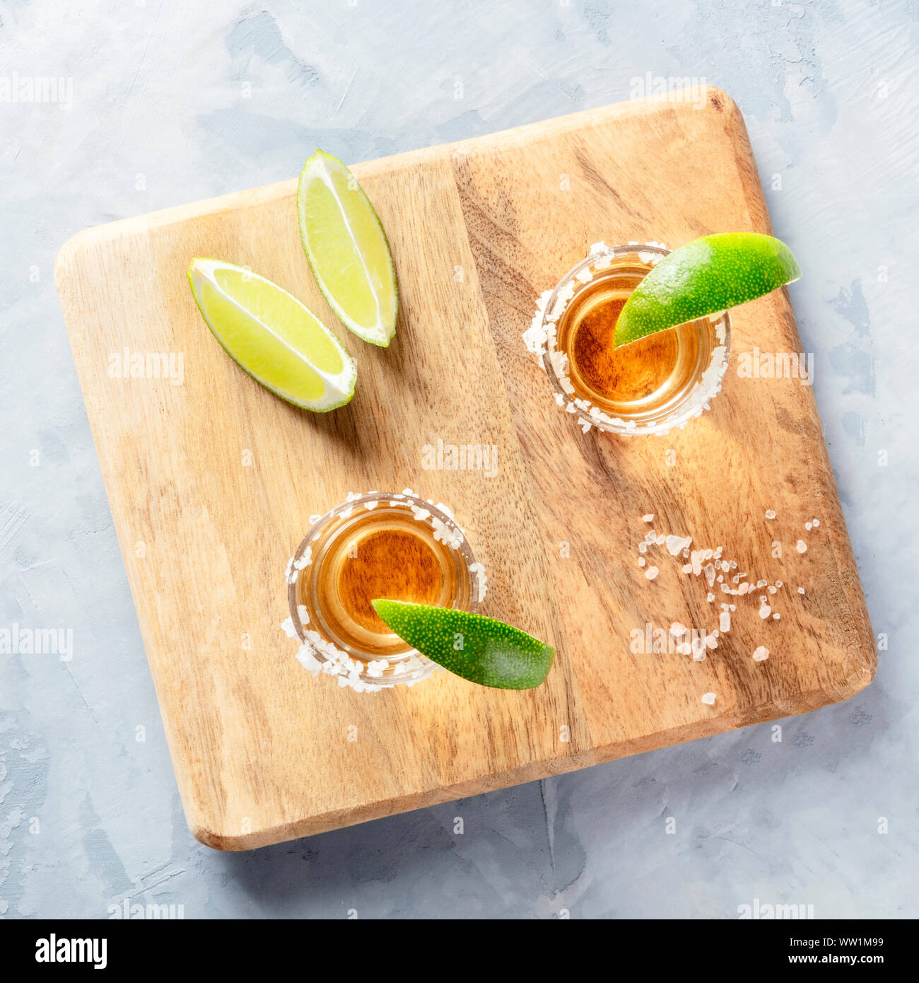 Golden tequila shots with lime slices and salt rims, overhead square ...
