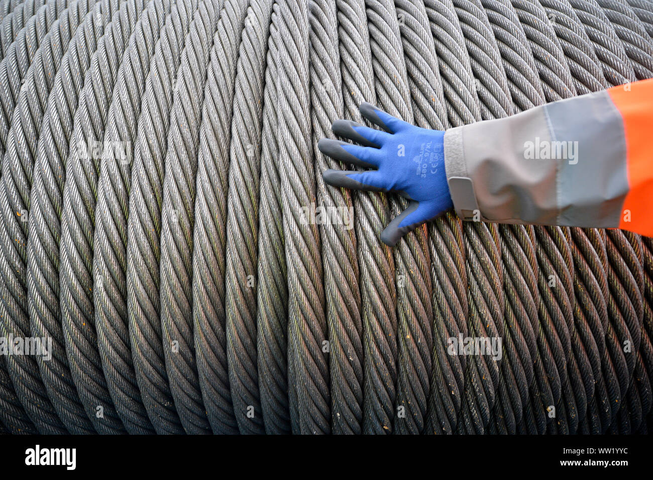 A construction worker shows how large the lifting cables are on-board ...