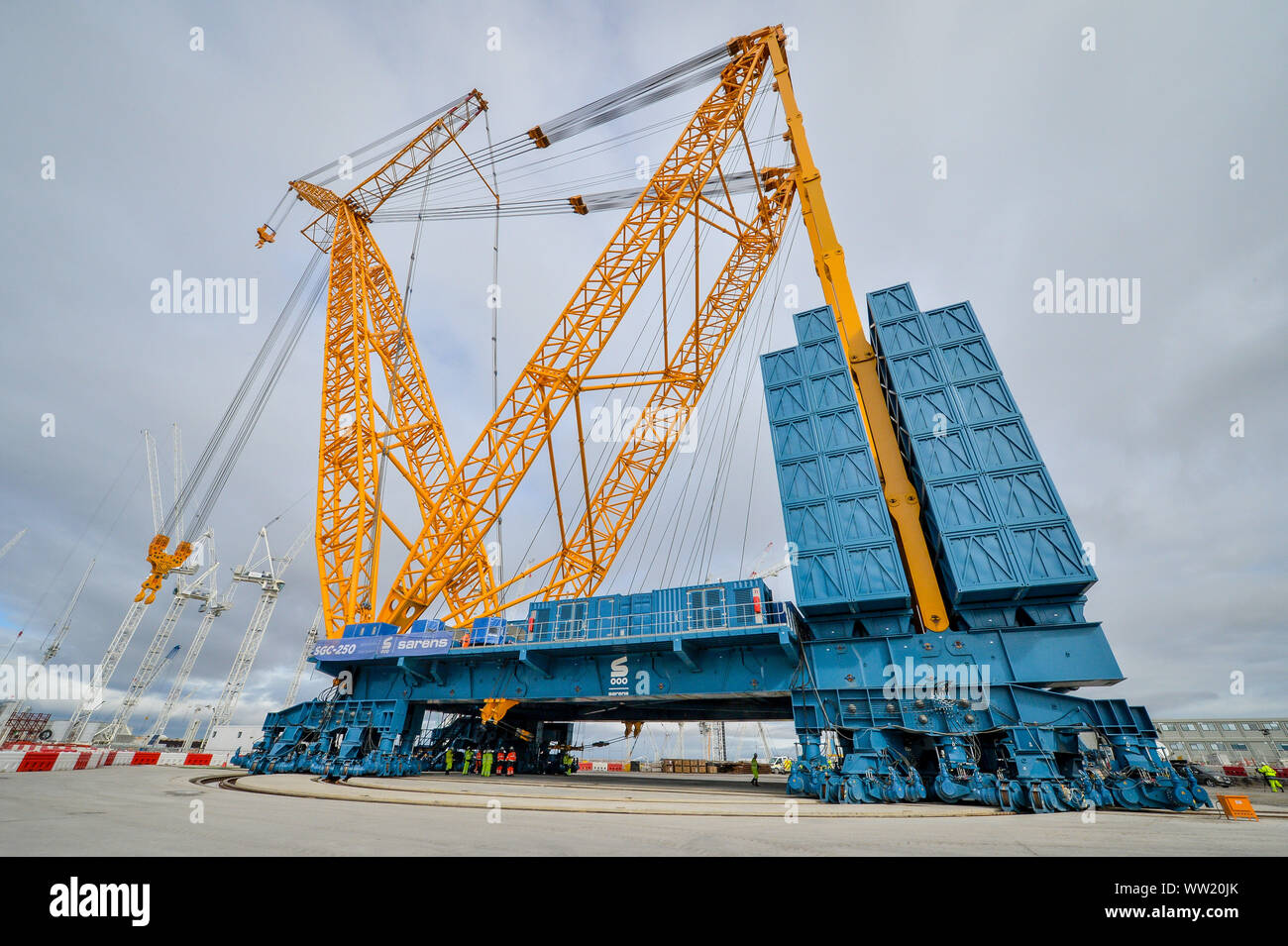 Construction workers are dwarfed as they stand underneath the base of "Big Carl", the world's ...