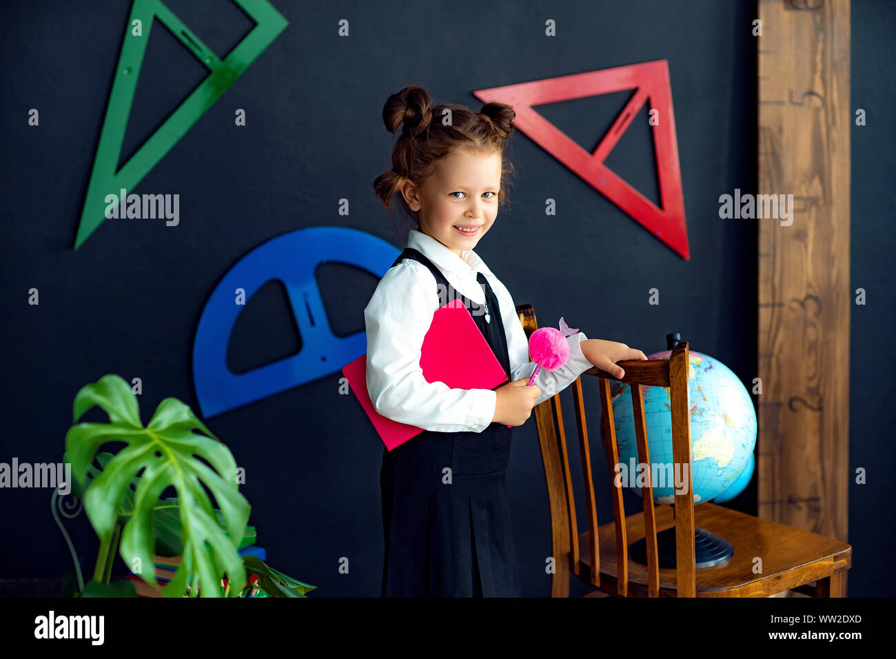 Clever little girl in school uniform and glasses smiling and looking at ...