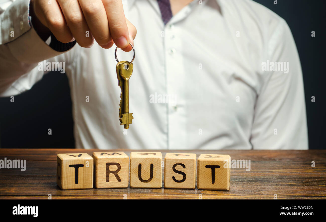 Wooden blocks with the word Trust and keys in the hands of a ...
