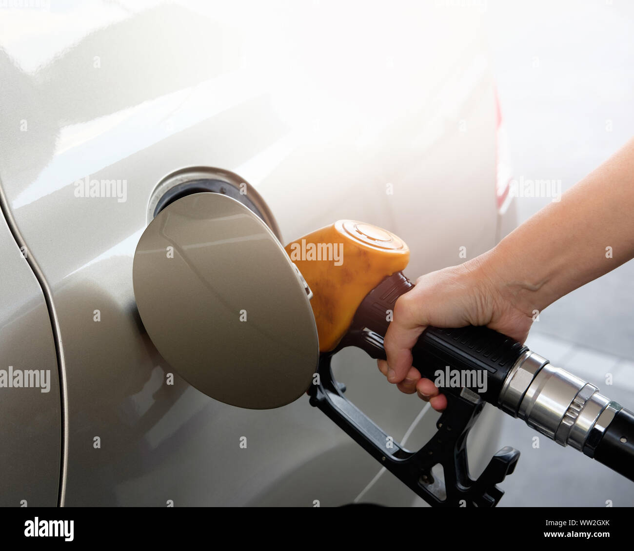 The gold car is filling the fuel at the oil station. Hand holding Fuel ...