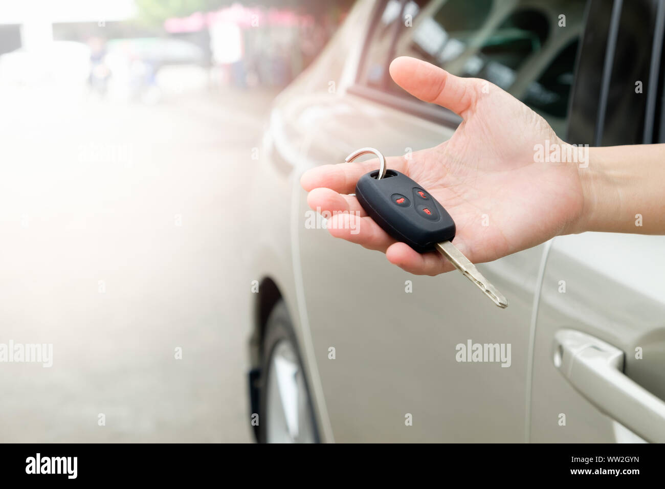 The hand of a woman holding a car key to be submitted to the driver of ...