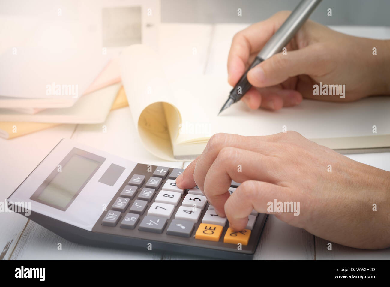 Hand writing and counting on calculator in office on wood desk about ...