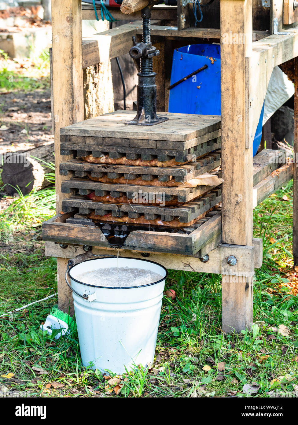 wooden press and bucket of freshly squeezed apple juice to produce ...