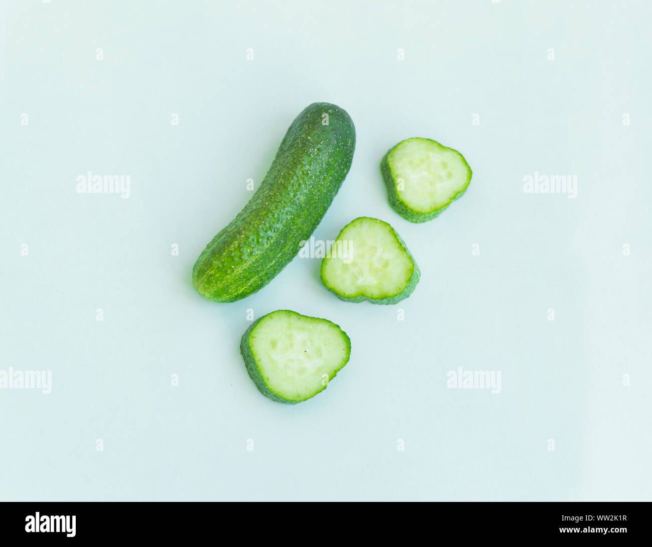 Fresh and sliced cucumbers on light blue background Stock Photo - Alamy