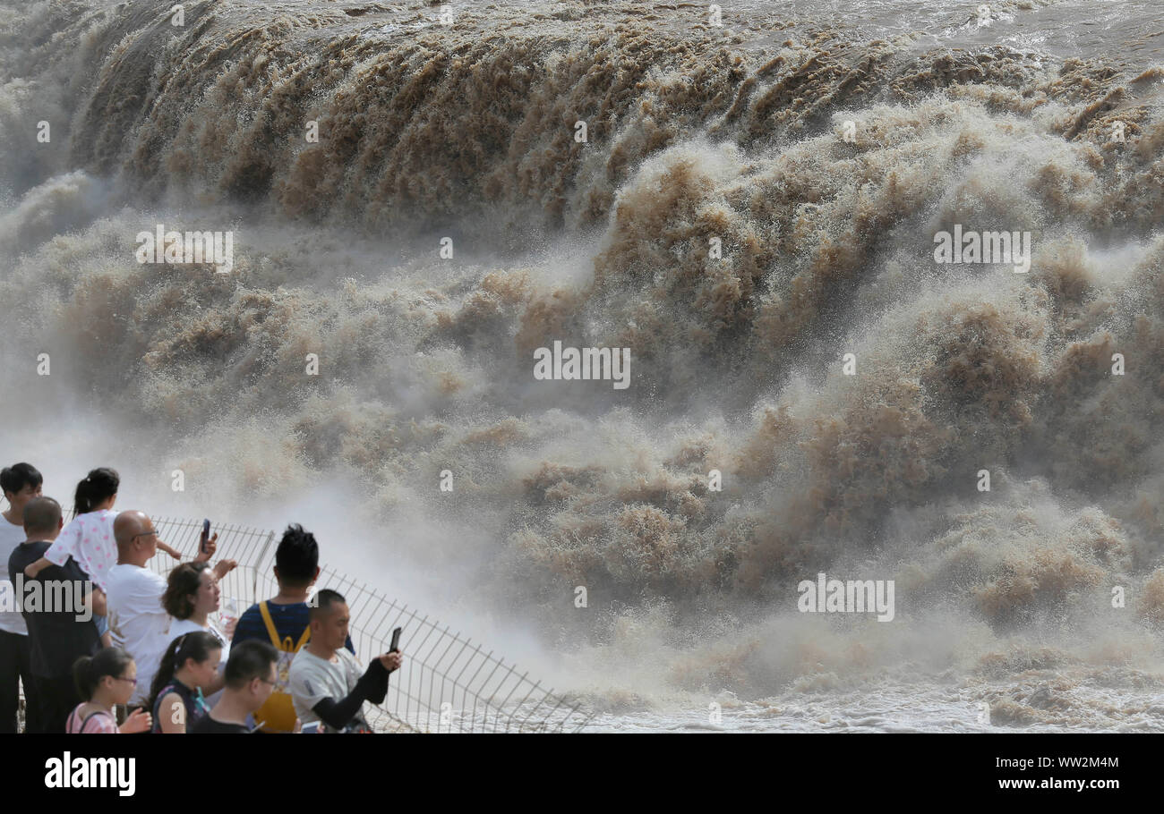 Tourists view the Hukou Waterfall on the Yellow River, also known as ...