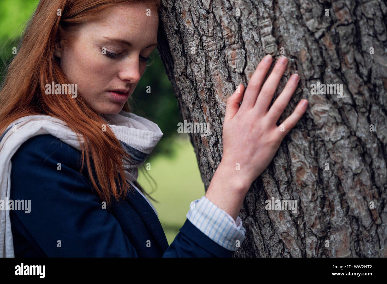 Woman leaning on tree trunk Stock Photo - Alamy
