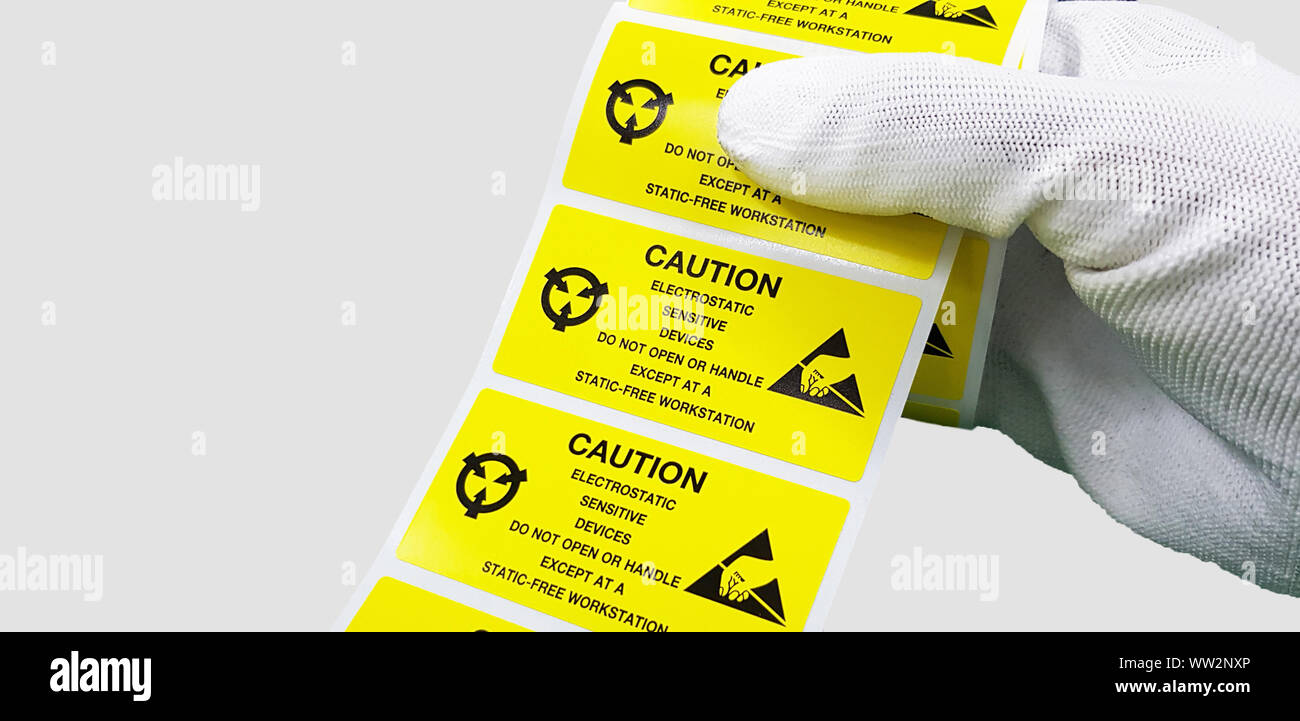 Hand holding ESD symbol label with antistatic gloves on gray background ...