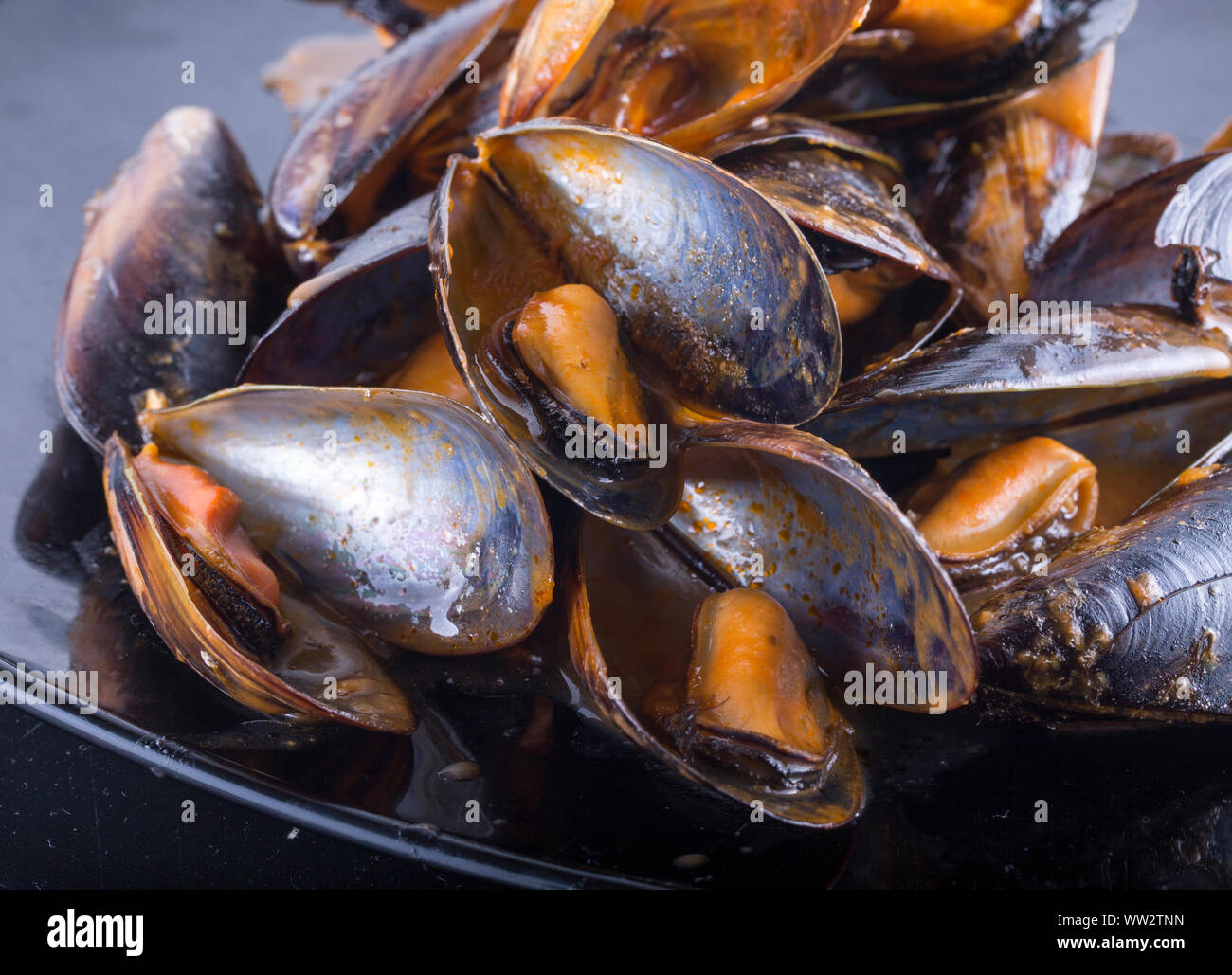 Open mussels over black plate, horizontal image Stock Photo - Alamy