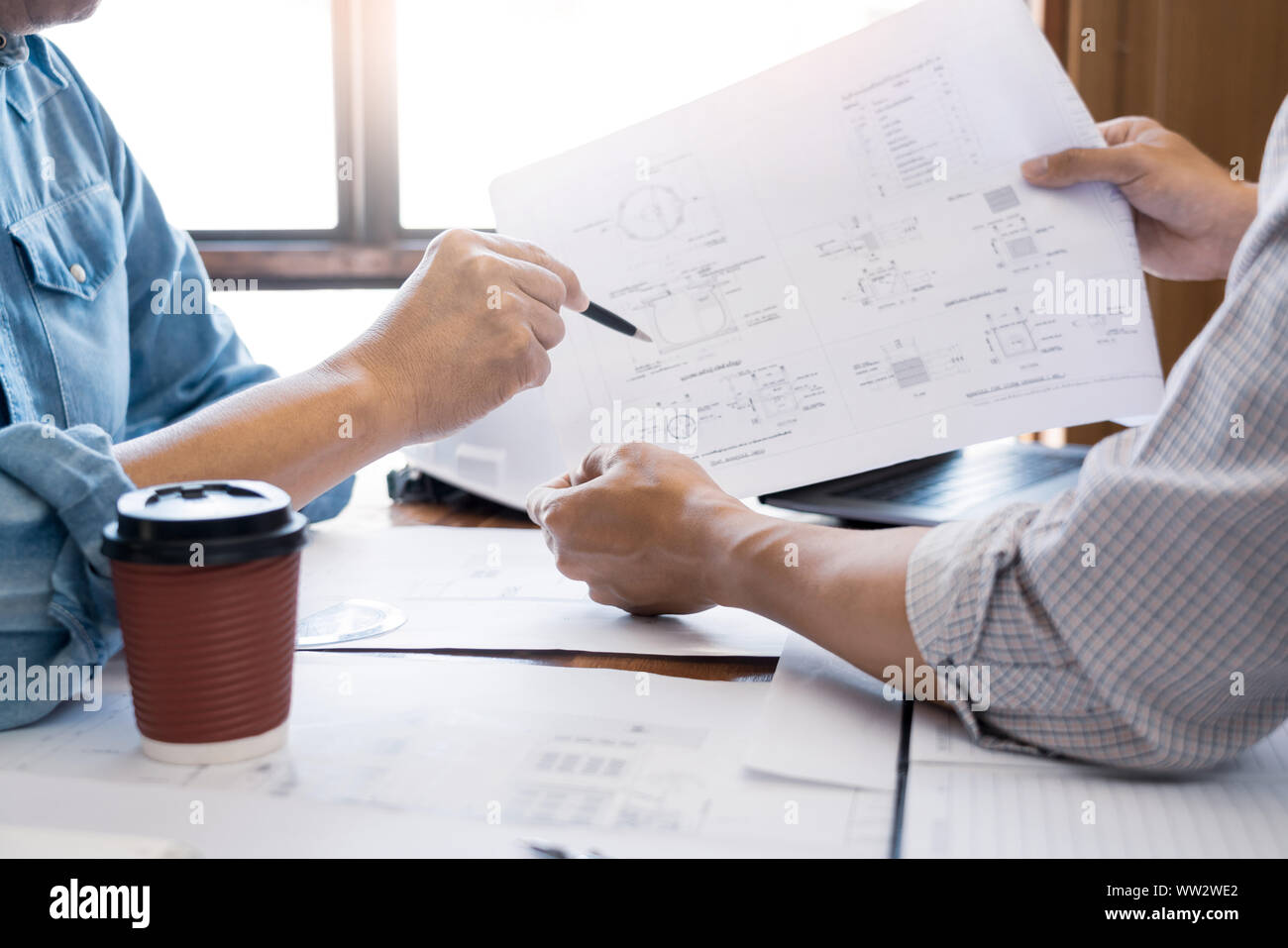 Architects engineer discussing at the table with blueprint, teamwork ...