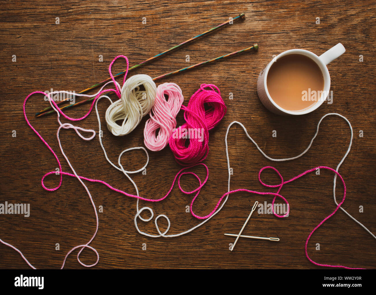 Wool and knitting needles on a dark wood table in a flat lay style ...