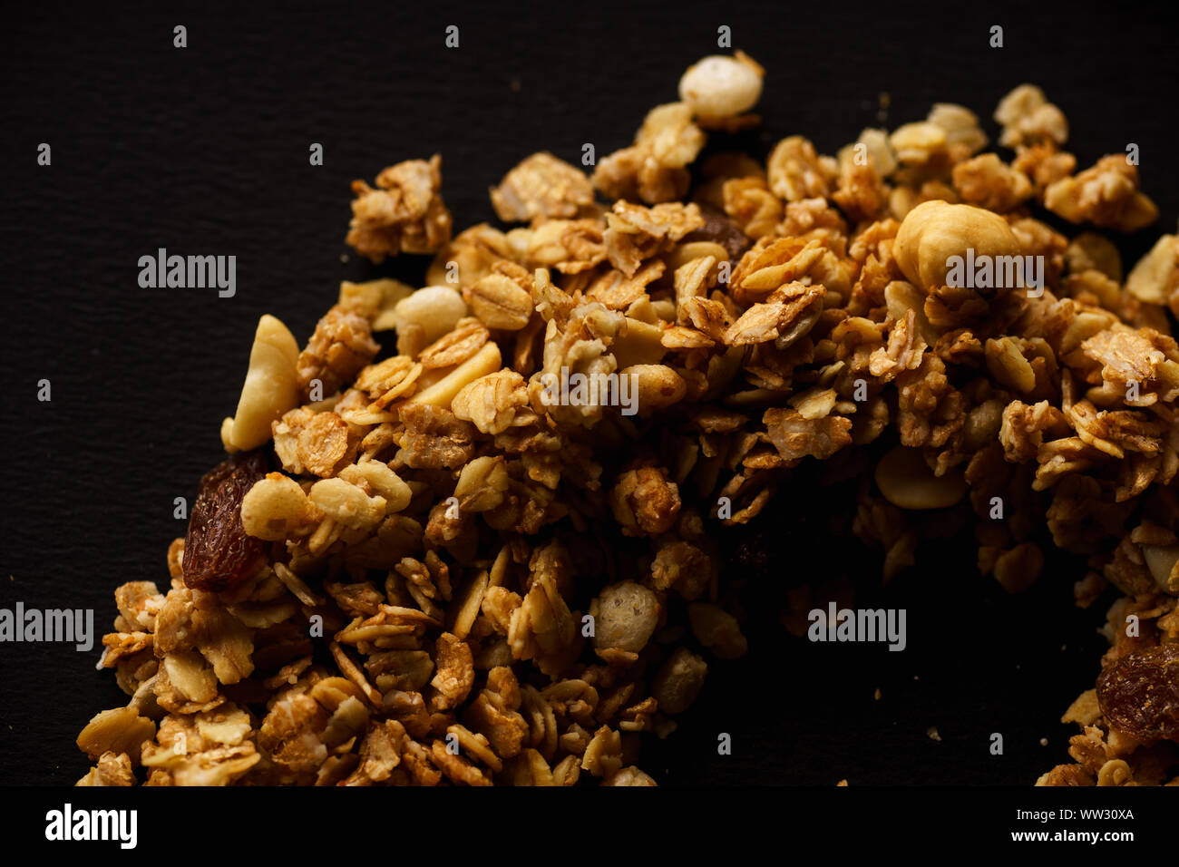 Overhead image of roasted granola laid in a form of a curve on black ...