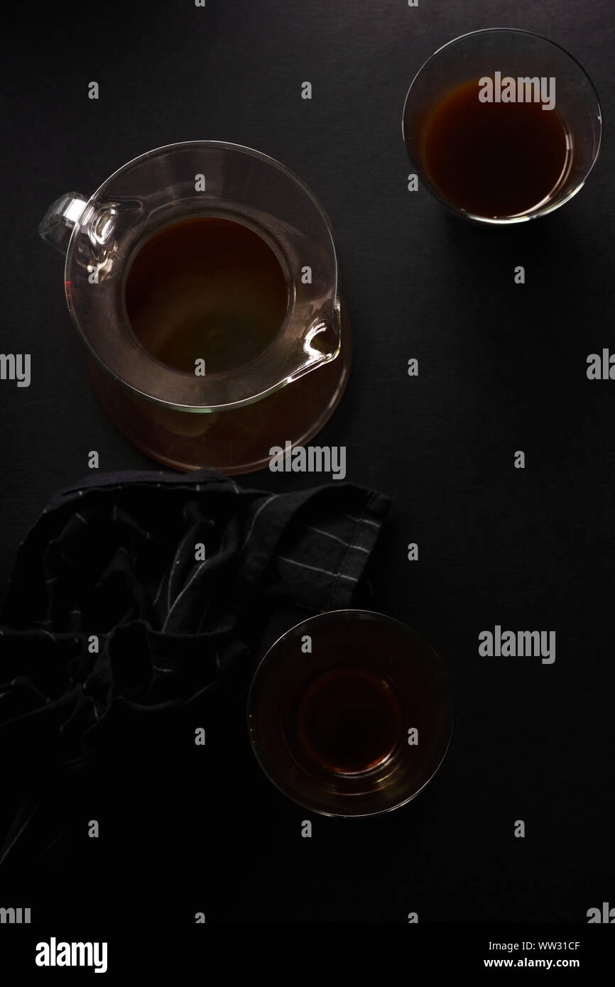 Pour over coffee in picther in two glasses on black background with ...