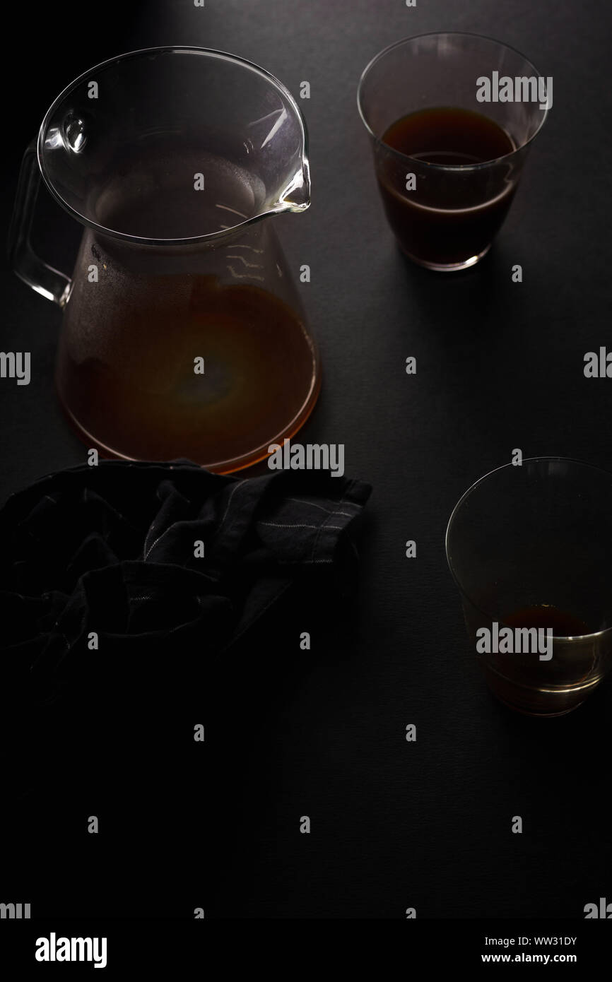 Pour over coffee in picther in two glasses on black background with ...