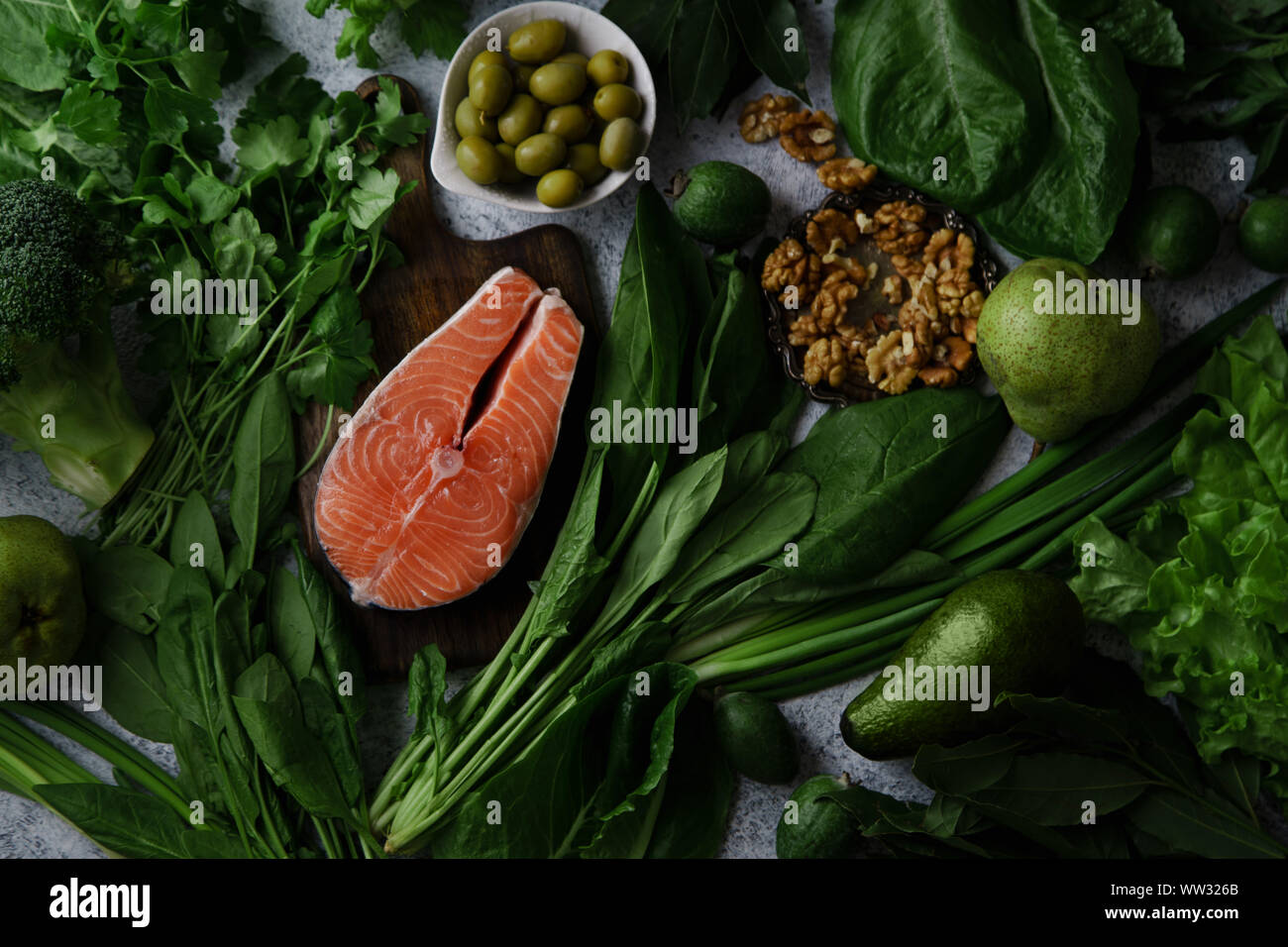 Fresh healthy food: vegetables, greens, fruits, walnuts and raw salmon ...