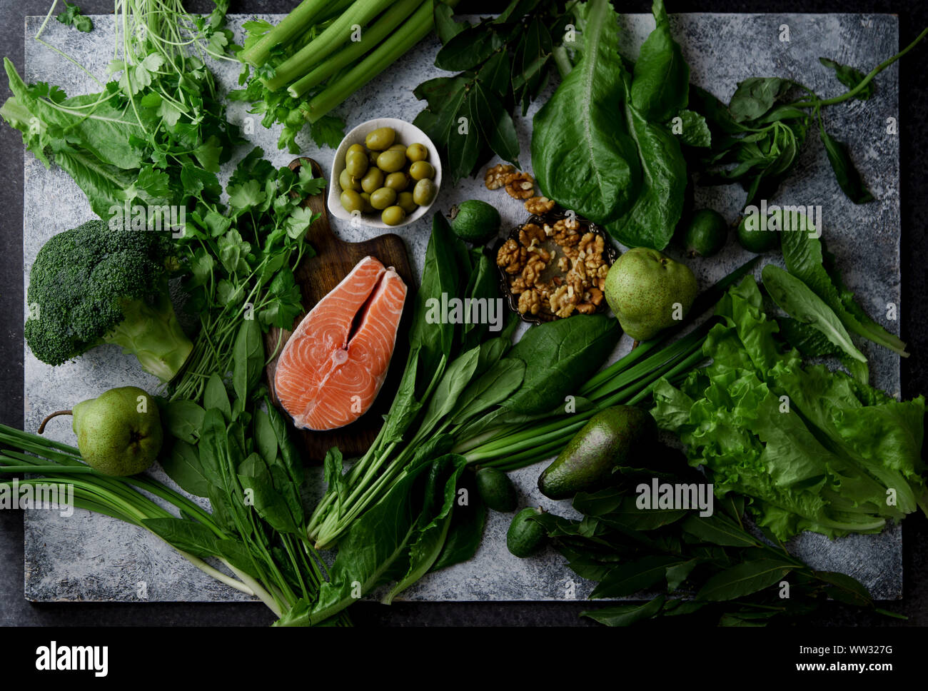 Fresh healthy food: vegetables, greens, fruits, walnuts and raw salmon ...