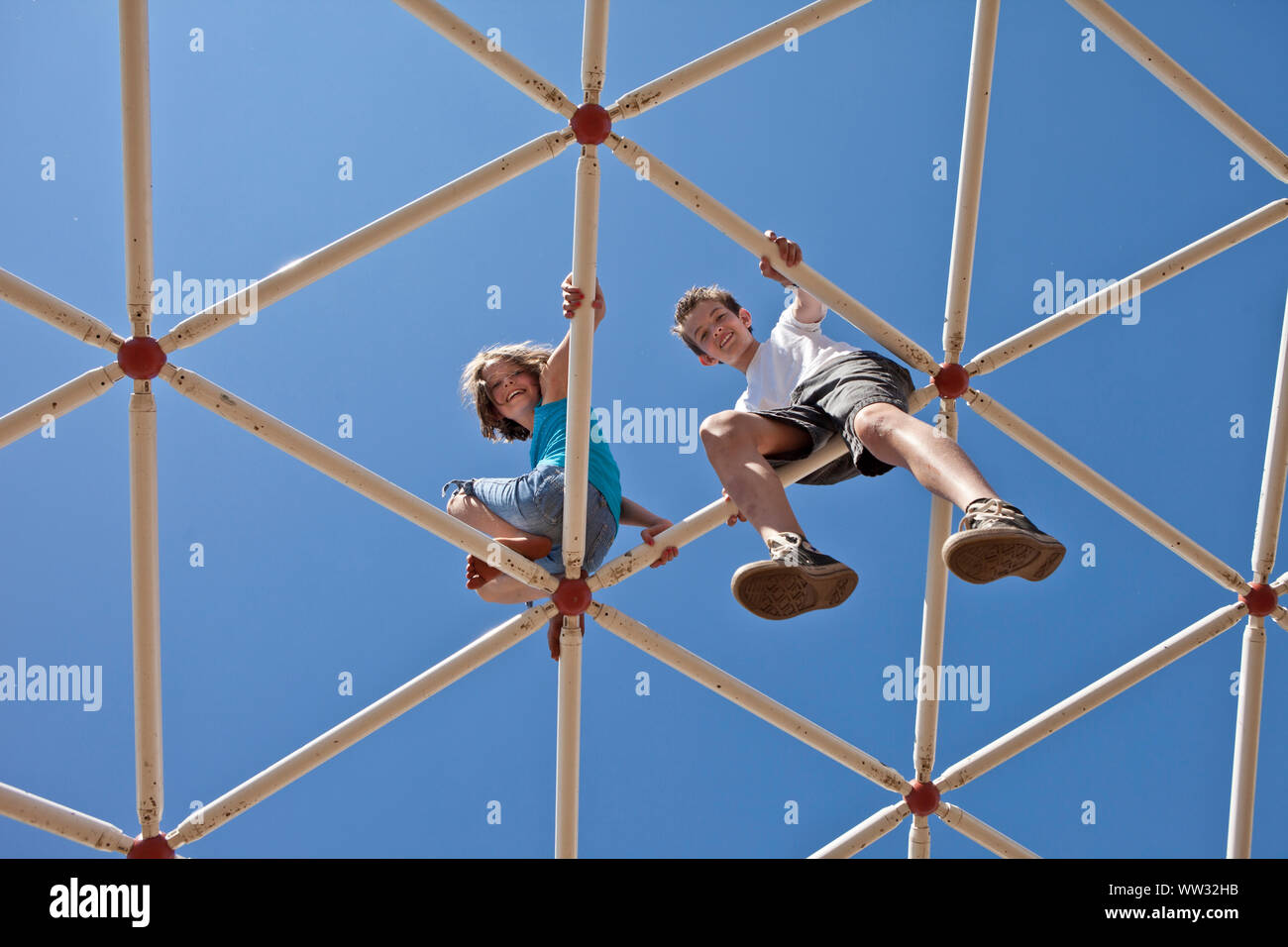 kids playing on monkey bars, view toward blue sky Stock Photo - Alamy