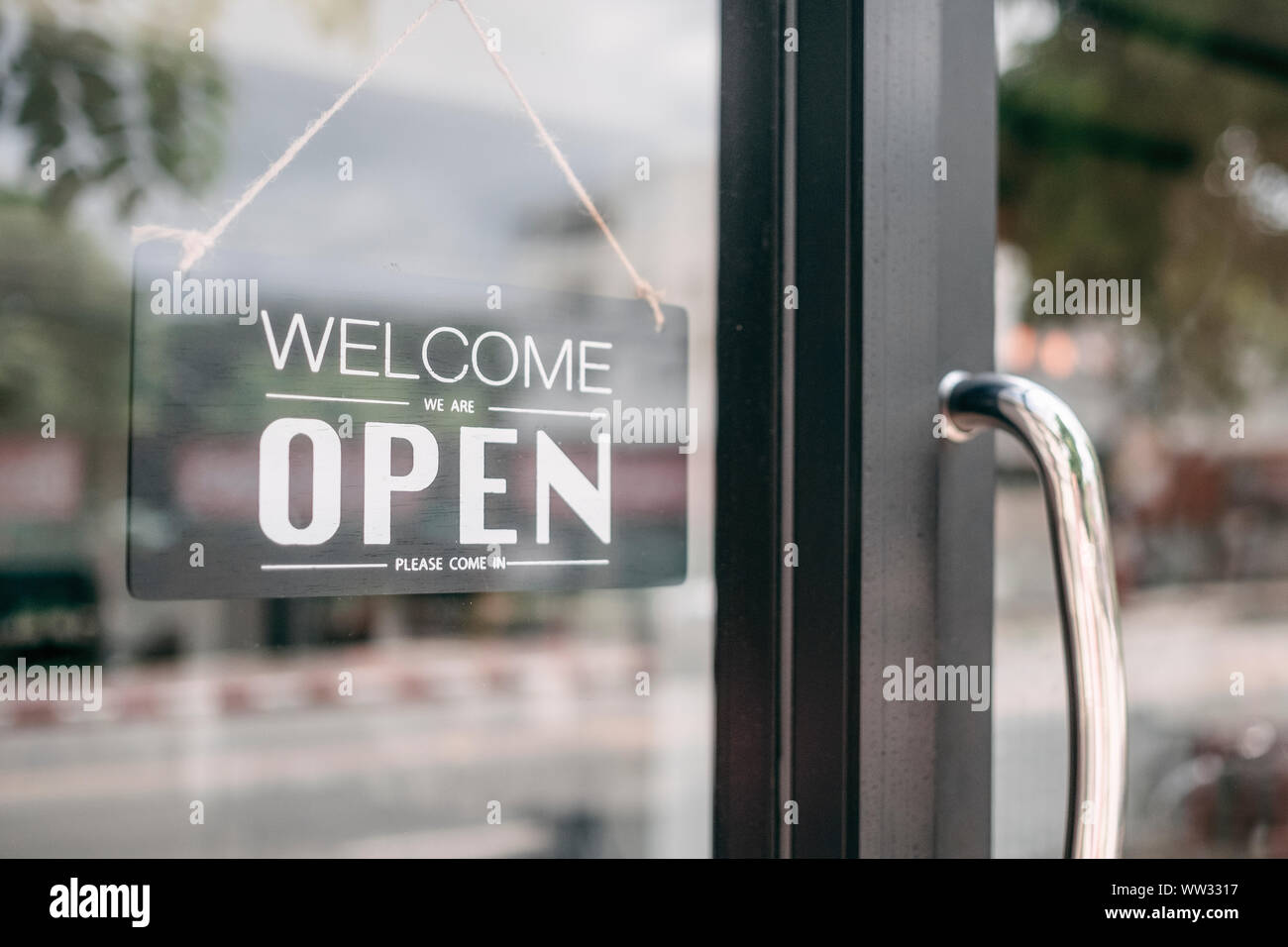 Closeup of open and welcome to store sign board hanging at the door ...