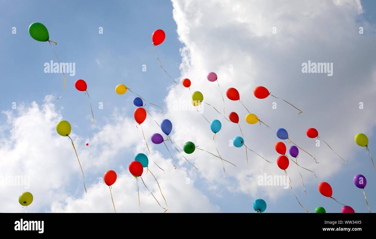 group of balloons fly into the blue sky with many white clouds symbol ...
