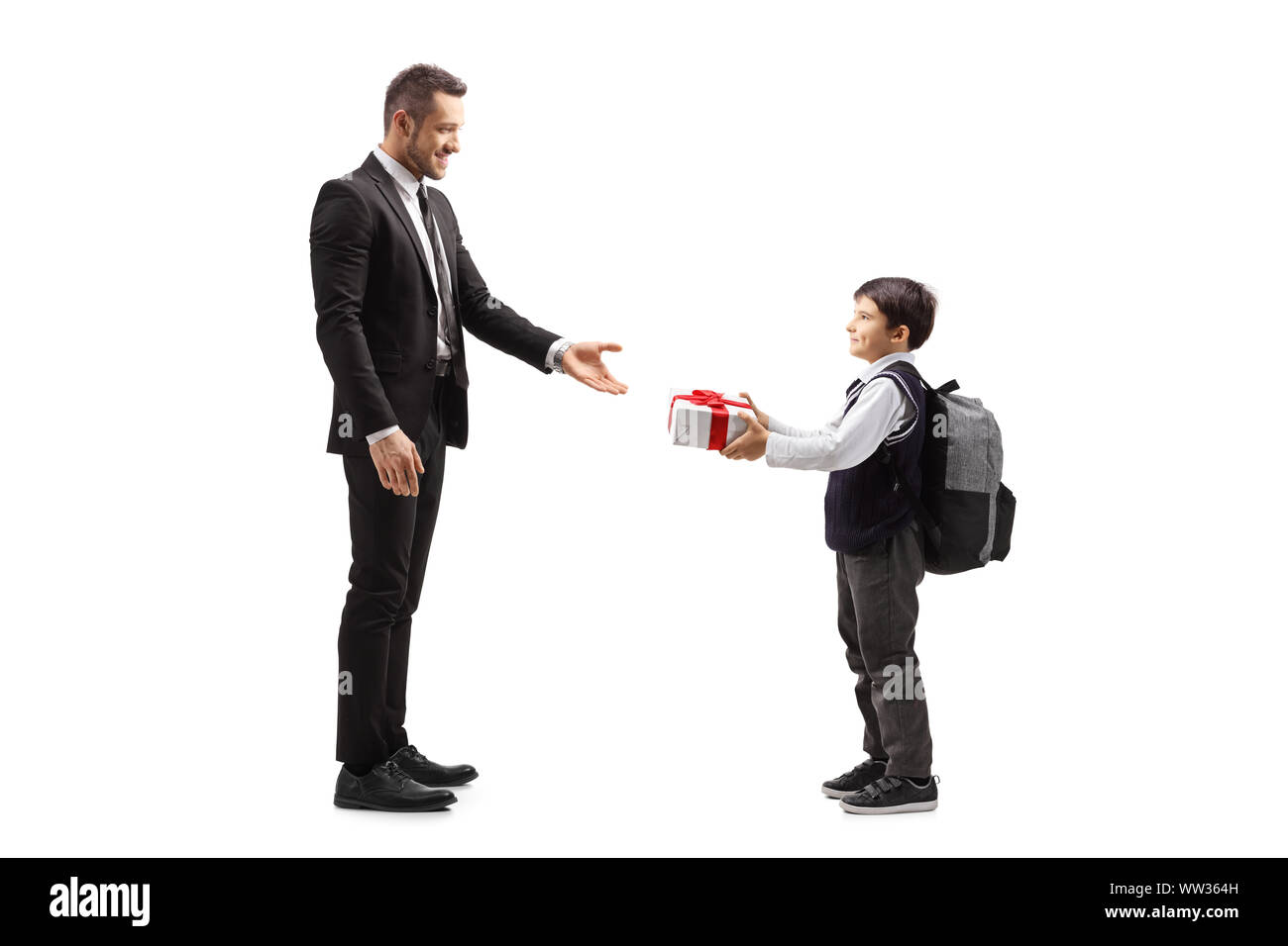 Full length profile shot of a schoolboy giving a present to a man in a ...