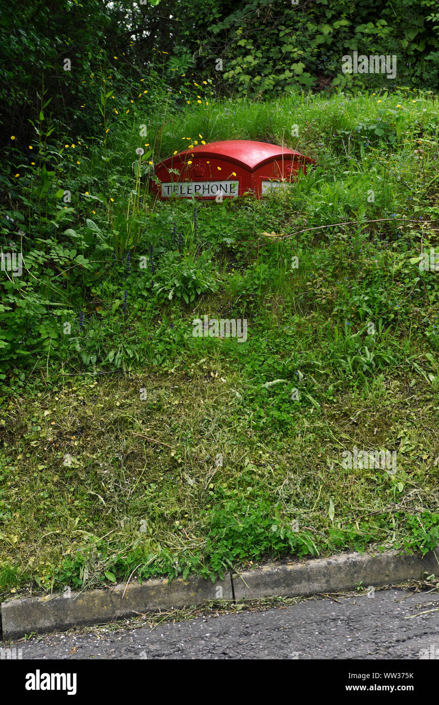 The top of a public telephone box buried in the grass bank beside the ...