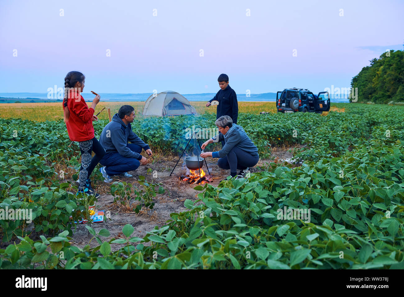 Family traveling and camping, twilight, cooking on the fire. Beautiful ...