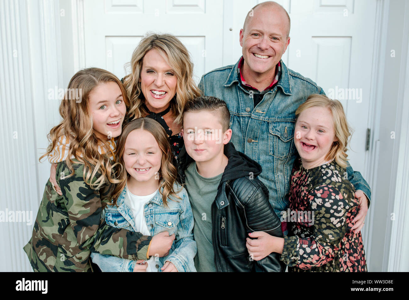 Joyful family in group hug in front of white door Stock Photo - Alamy